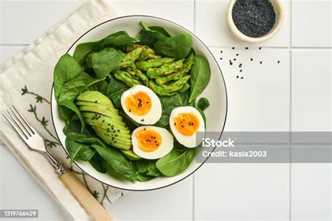 아보카도 아스파라거스 검은 참깨와 가벼운 슬레이트 돌 또는 콘크리트 배경에 접시에 시금치구를 구겨진 신선한 야채 샐러드 그릇에 균형 잡힌 점심 맨 위 보기입니다 모의 0명에