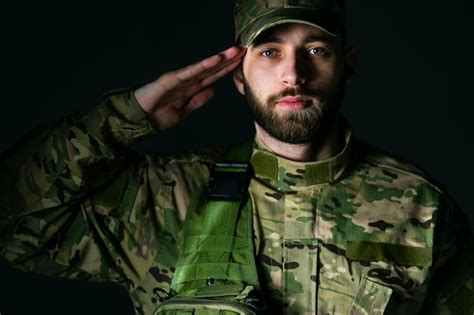 Soldado do corpo de fuzileiros navais fazendo um gesto de saudação contra um fundo escuro Foto