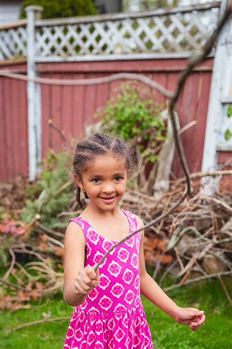 A Pretty Young Girl Playing Outdoors With A Long Stick By Stocksy