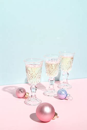 크리스마스 공과 파란색과 분홍색 파스텔 배경에 샴페인와인 잔 미니멀리즘 아트 구성 크리스마스와 새해 휴일 파티의 개념 0명에