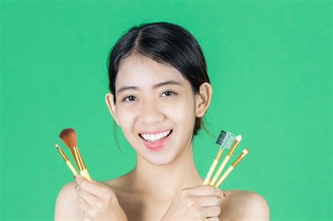 녹색 고립 된 배경 위에 브러시로 메이크업을 적용 젊은 아시아 여성의 아름다움 얼굴 건강 하고 화장품 개념 건강관리와 의술에