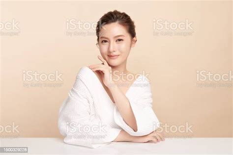 베이지 색 배경에 깨끗한 신선한 피부를 가진 아름다운 젊은 아시아 여성 얼굴 관리 얼굴 치료 화장품 아름다움과 스파 아시아 여성