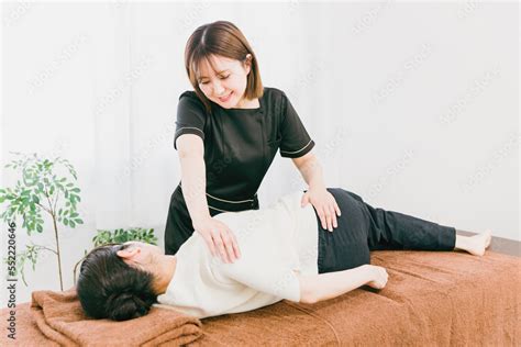 骨盤矯正をするマッサージ師・セラピスト・整体師・理学療法士のアジア人女性 素材庫相片 Adobe Stock