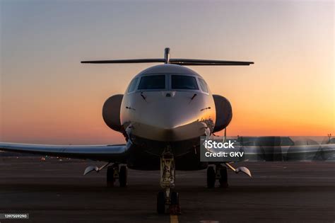 경치 좋은 정면 전망 현대 고급 비싼 개인 제트 비행기 주차 공항 택시 격납고 따뜻한 화려한 극적인 저녁 따뜻한 일몰 태양 빛