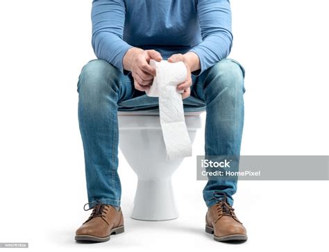 남자는 화장실에 앉아 화장지 롤을 손에 들고 흰색 배경에 고립되어 있습니다 파일에 격리 경로가 포함되어 있습니다 가정 생활에 대한 스톡 사진 및 기타 이미지 Istock