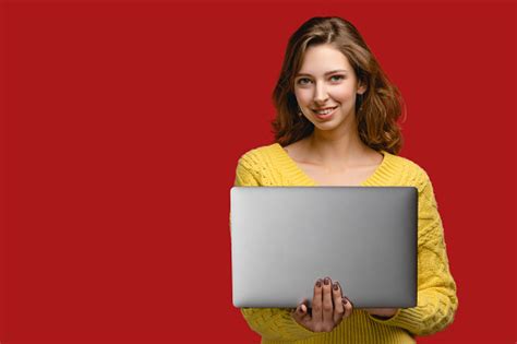 빨간 배경에 여자의 스튜디오 초상화 온라인 작업에 대 한 노트북 컴퓨터를 사용 하 여 사람 현대인과 개념 노란색 점퍼를 입고 프리랜서에서 일하는 패션 소녀 복사 공간이 있는