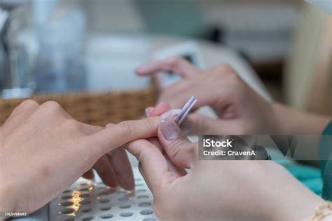 손톱 매니큐어 세부 사항 파일 또는 브러시 항목 여성의 아름다운 손톱 관리 과정입니다 뷰티 네일 살롱에서 전문 네일 파일로 손톱을 정리하는 여성 손의 근접 촬영 2명에 대한
