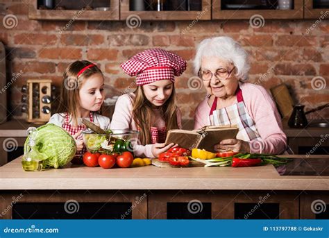 Abuelita Con Dos Nietas Que Leen Receta Foto De Archivo Imagen De