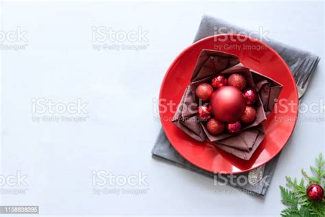 붉은 접시 연꽃 모양의 갈색 냅킨과 회색 나무 배경에 공 크리스마스 테이블 설정 휴일 장식 개념입니다 플랫 레이 맨 위 보기