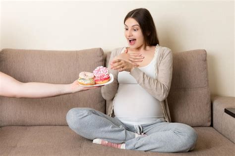 Marido Oferece Rosquinhas Para Sua Esposa Grávida Relaxando No Sofá Em