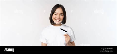 Portrait Of Korean Smiling Girl Bank Client Showing Credit Card With