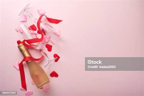 샴페인 병 선물 상자 빨간 리본 분홍색 배경에 빈 메모 모형이있는 봉투가있는 발렌타인 데이 인사말 카드 인사말을 위한 공간이 있는 최고 보기 카피 공간이 있는 인사말 카드