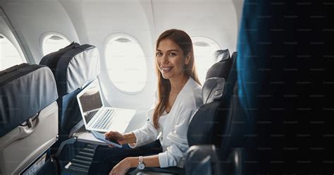 비행기 현창 옆에 앉아 있는 자신감 넘치는 여성 승객 앞에 노트북을 들고 스마트폰을 손에 들고 있다 사진 Unsplash의 좌석 이미지