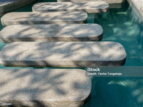 화창한 날에는 리조트의 깨끗하고 맑은 물 수영장을 가로질러 나뭇잎 그늘이 있는 빈 테라조 통로 계단이 있습니다 여름 배경에 바깥