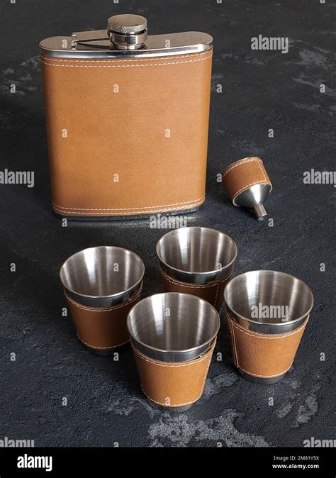 Hip Flask Made Of Stainless Steel And Brown Leather With Cups On A Dark