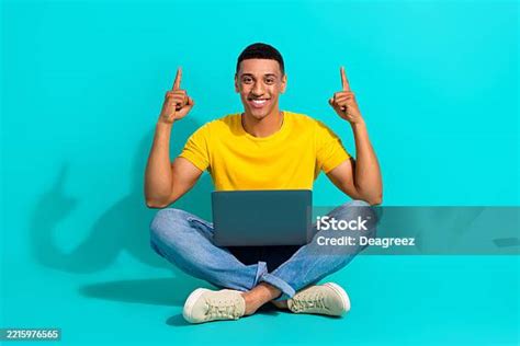 잘 생긴 남자의 전체 크기 사진은 바닥 사용 넷북이 청록색 배경에 고립 된 빈 공간을 손가락으로 나타냅니다 T 셔츠에 대한 스톡 사진 및 기타 이미지 Istock