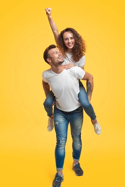 Premium Photo Man Carrying Cheerful Woman On Back