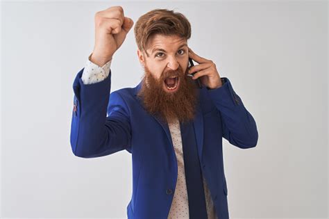 고립 된 흰색 배경을 통해 스마트 폰에 말하는 젊은 빨간 머리 아일랜드어 사업가 짜증과 분노로 고함 미친 고함 분노 개념 감정에