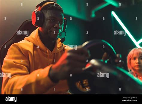 Black Teenager Sitting In Gaming Chair Wearing Headphones Focused On