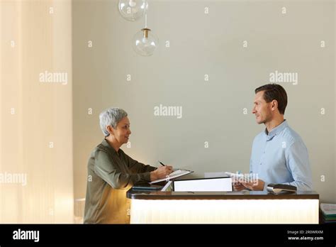 Side View Portrait Of Smiling Senior Woman Filing In Papers At Admin