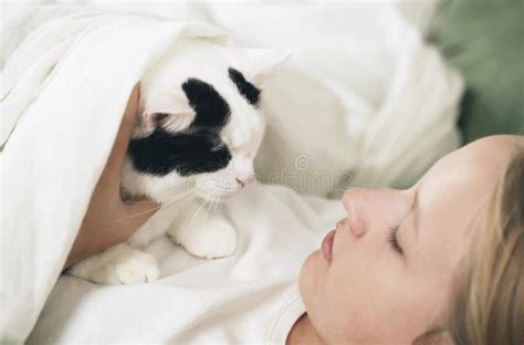 A Teenager Girl Lies With A Cat Under A Blanket Stroking Him Stock