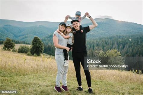 들판에서 함께 시간을 보내는 행복한 젊은 가족의 초상화 엄마 아빠는 아기 아들과 딸을 안고 산의 풀밭에 서 있다 가족 휴가의 개념입니다 어머니 아버지는 가을날에 아이들을