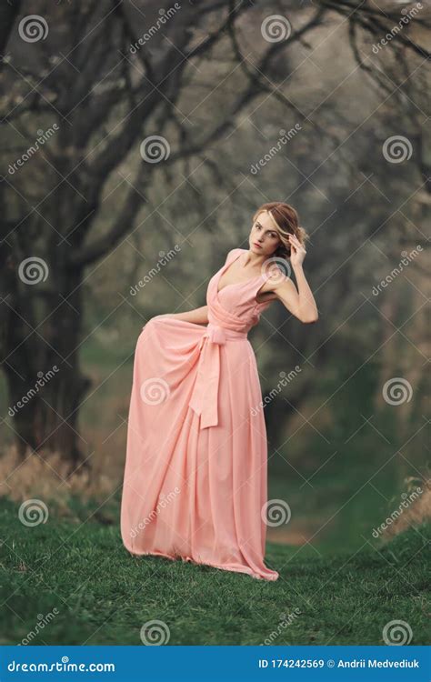 Full Length Young Stylish Woman Near Blossoming Tree In The Spring Park