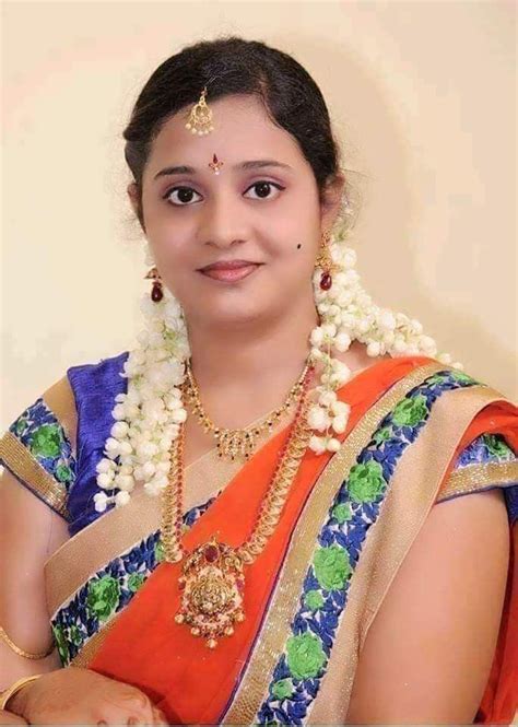 A Woman In An Orange And Blue Sari Is Posing For The Camera With Her