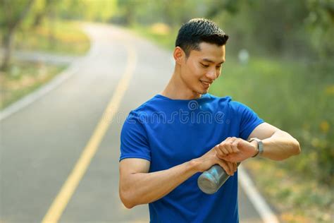 Satisfied Athletic Man In Sportswear Looking At His Smartwatch Checking His Heart Rate And