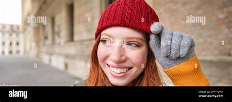 Headshot Of Happy Redhead Girl With Freckles Wears Red Hat And Gloves