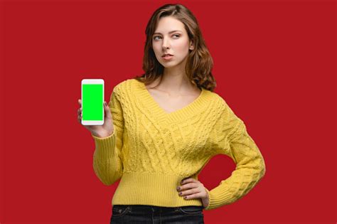 스튜디오에서 빨간색 배경에 스마트 폰을 가진 젊은 여성 그녀는 노란색 스웨터를 입고 설계를 위한 공간을 복사합니다 감정이 있는 개념 14에 대한 스톡 사진 및 기타 이미지