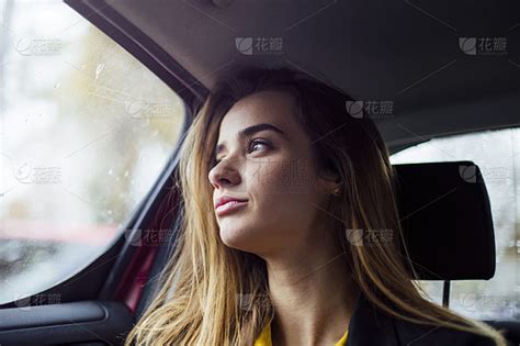 年轻漂亮的女商人坐在汽车后座上望着窗外