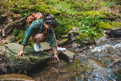触摸山河之水的女人徒步旅行的概念