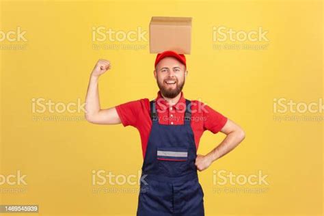 파란색 제복을 입은 택배 남자가 머리에 골판지 상자를 들고 서서 카메라를 바라보며 팔을 들었다 나름에 대한 스톡 사진 및 기타