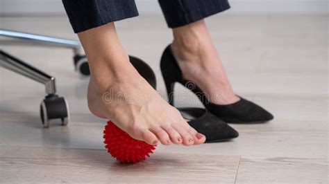 Business Woman Massages Her Feet On A Massage Ball With Spikes Stock