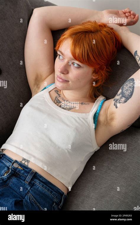A Woman With Hairy Armpits Lying On A Sofa With Her Arms Above Her Head