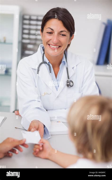 Smiling Doctor Giving A Prescription To A Patient In Her Medical Office
