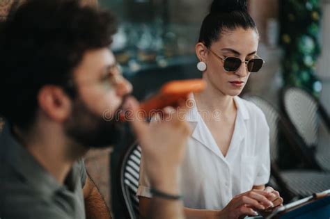 Business Partners Discussing New Project While Analyzing Statistics In Modern Coffee Shop Stock