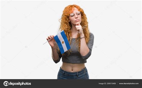 Young Redhead Woman Holding Flag Argentina Serious Face Thinking