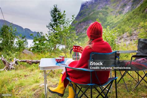 텐트 앞 캠핑 의자에 앉아 커피 한 잔과 노르웨이 노르들란드 센자 섬 자연에서 야생 캠핑을 즐기는 여성 담요를 가진 여자 모자 캠핑에 대한 스톡 사진 및 기타 이미지