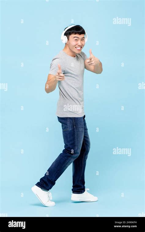 Happy Young Asian Man Wearing Wireless Headphones Listening To Music
