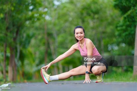 초상화 건강한 라이프 스타일 개념으로 도시 자연 공원에서 야외에서 조깅 운동을하기 전에 스트레칭을하는 야외 복장의 쾌활한 아시아