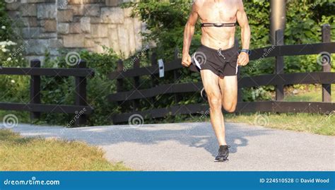 Shirtless Runner Wearing Black Heart Rate Monitor Running On Tar Path