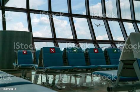 공항 터미널의 출발 라운지에 빈 좌석 코로나바이러스와 승객의 안전을 위해 거리를 유지합니다 유리 창을 통해 비행 비행기를 보았다
