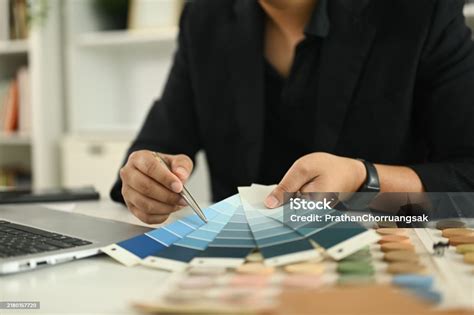 한 인테리어 디자이너가 책상에서 새로운 디자인 프로젝트를 진행하면서 컬러 차트를 검토하고 있습니다 25 29세에 대한 스톡 사진