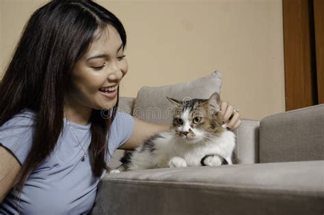 Pretty Asian Woman Hug A Cat And Sit On Couch With Happy Emotion
