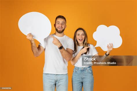 유쾌한 밀레니얼 세대의 유럽 커플이 활기찬 대화를 상징하는 말풍선을 즐겁게 들고 있습니다 높게 들기에 대한 스톡 사진 및 기타 이미지 높게 들기 대화 풍선 문자 기호
