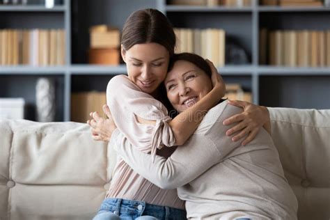 Adult Daughter Cuddling Cherish Her Mother Women Seated On Couch Stock