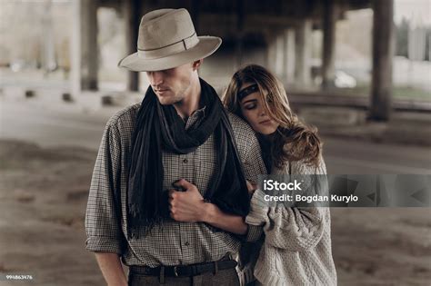 Boho 세련 된 옷과 흰 모자와 스카프에 잘생긴 카우보이 남자를 포옹 하는 하얀 드레스에 로맨틱 집시 여 인 가을에 대한 스톡