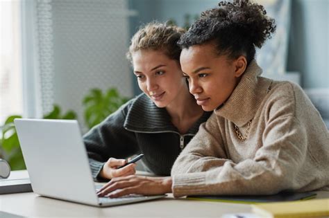 Premium Photo Two Young Colleagues Sitting At Table In Front Of